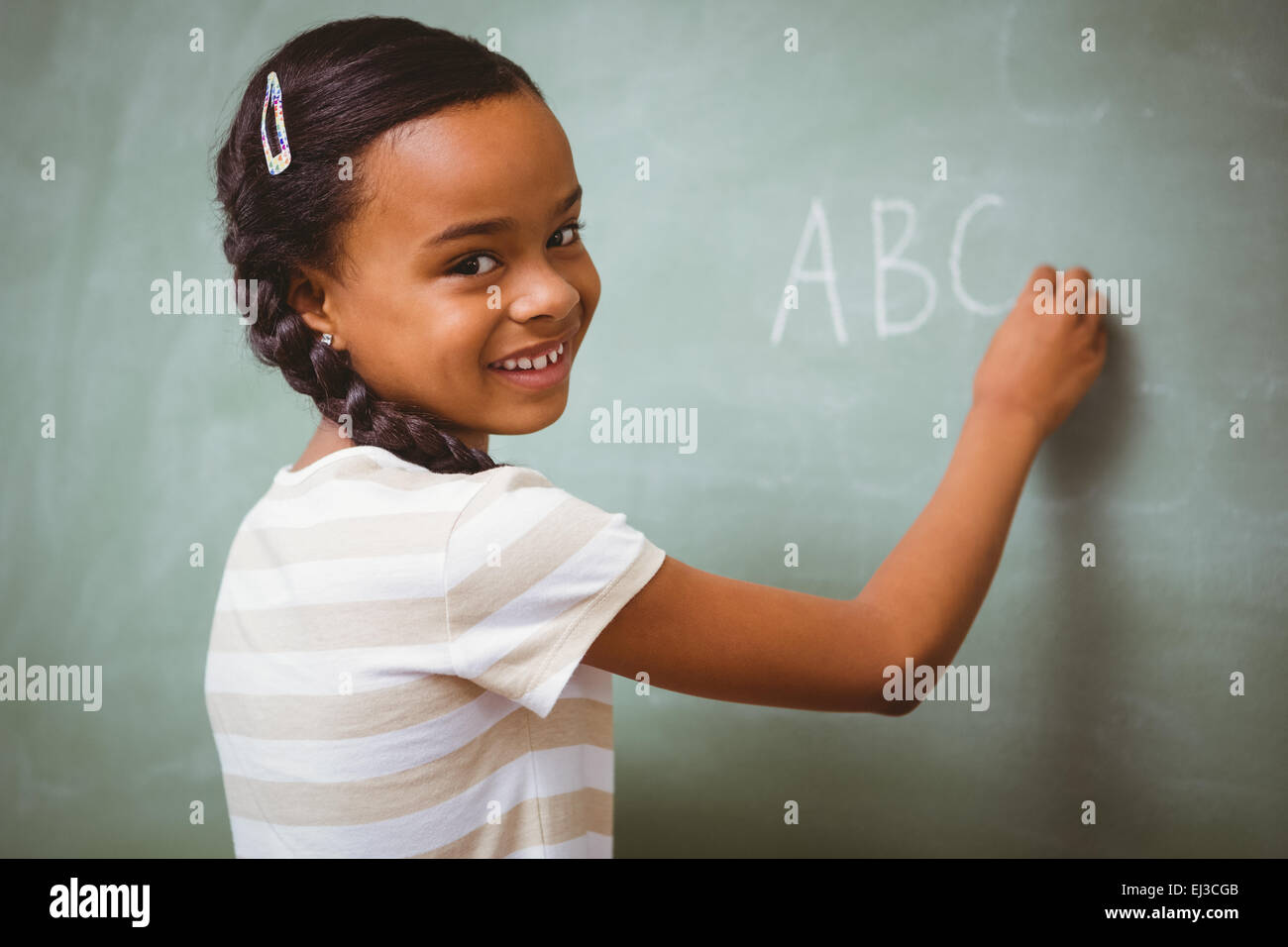 Cute little girl writing ABC on blackboard Stock Photo - Alamy