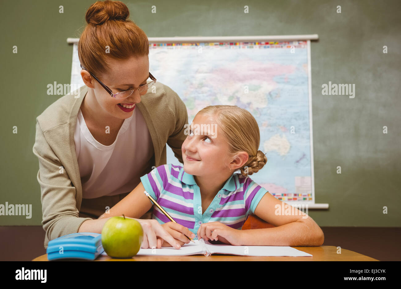 Teacher assisting girl with homework in classroom Stock Photo - Alamy