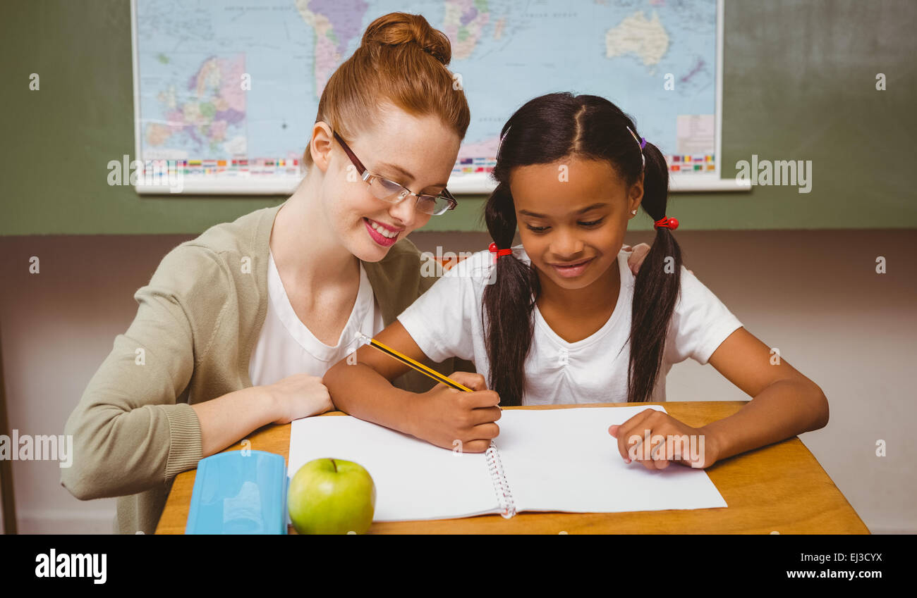 Teacher assisting girl with homework in classroom Stock Photo - Alamy