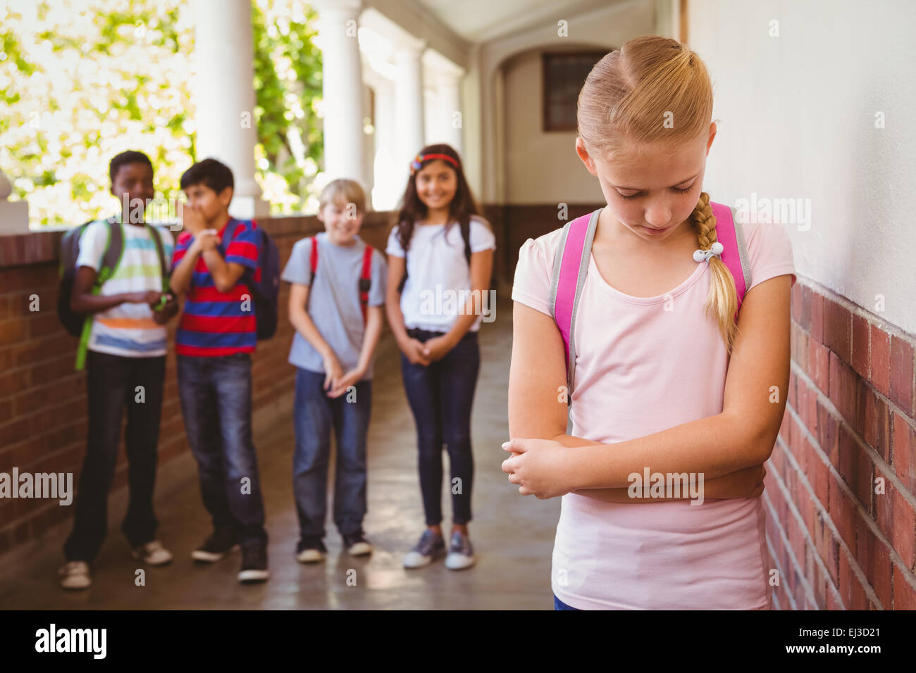 Sad schoolgirl with friends in background at school corridor Stock ...