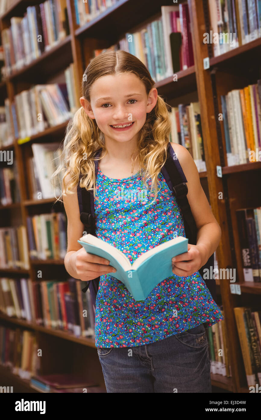 Cute little girl reading book in library Stock Photo - Alamy