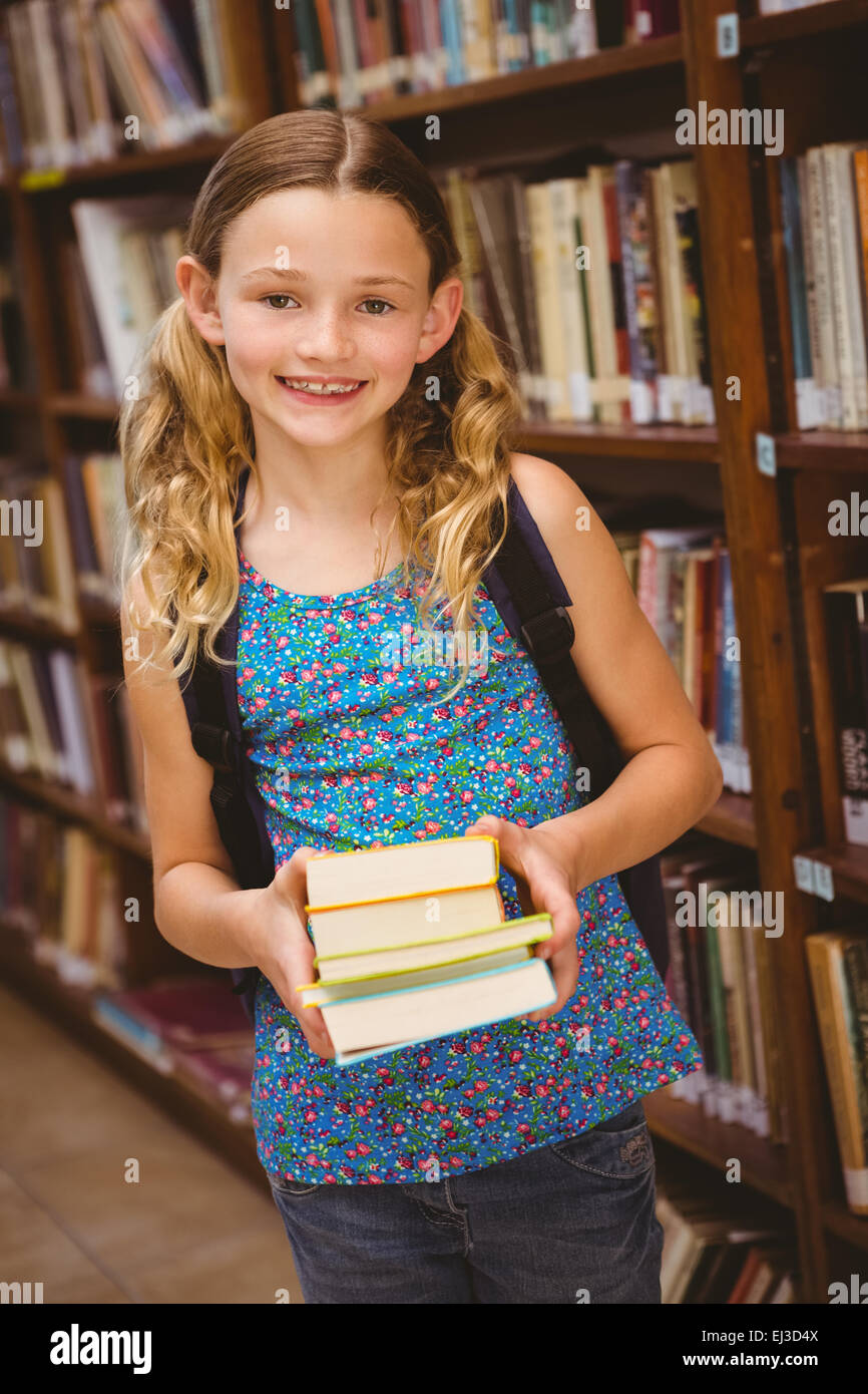Cute little girl holding books in library Stock Photo - Alamy