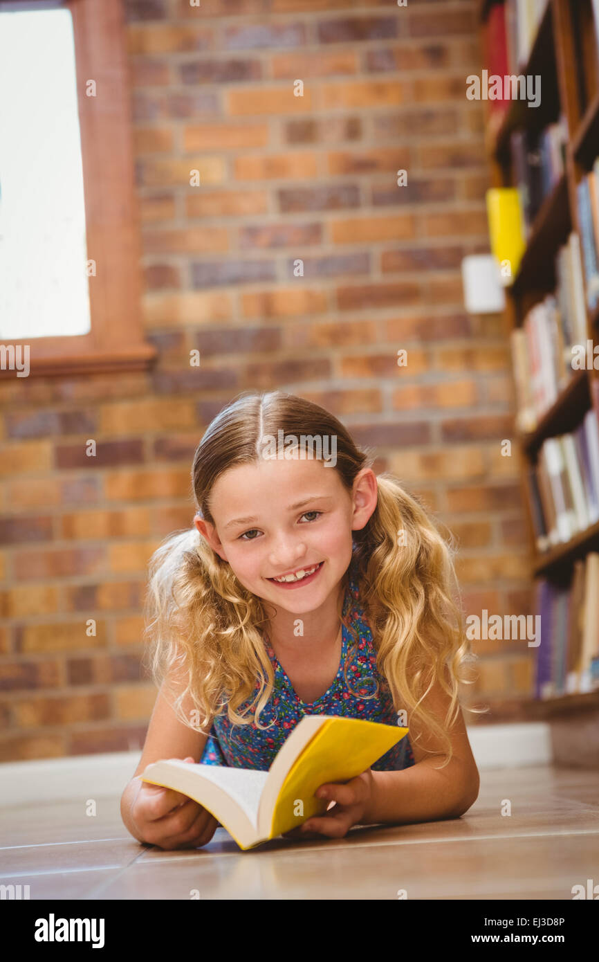 Cute little girl reading book in library Stock Photo - Alamy