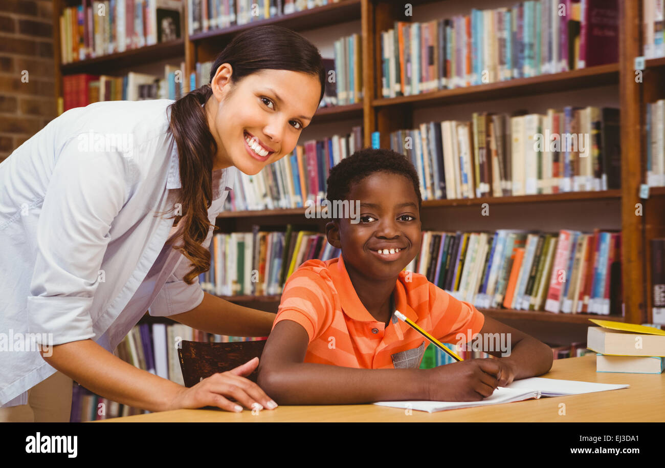 Teacher assisting boy with homework in library Stock Photo - Alamy