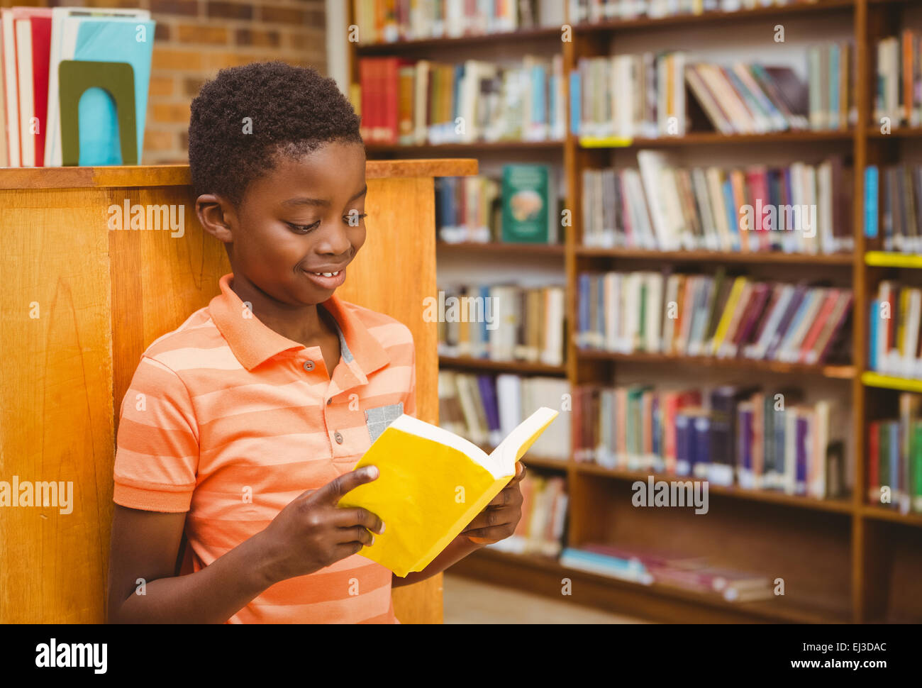 Cute boy reading book in library Stock Photo - Alamy
