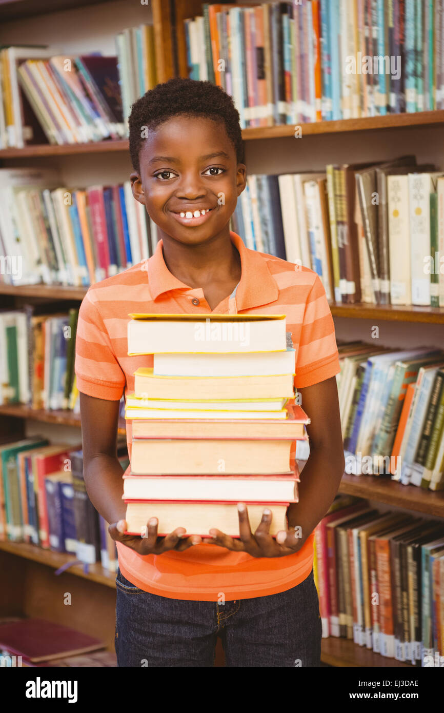 Portrait of cute boy carrying books in library Stock Photo - Alamy