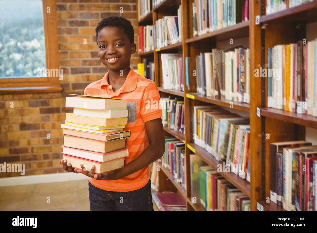 Portrait of cute boy carrying books in library Stock Photo - Alamy