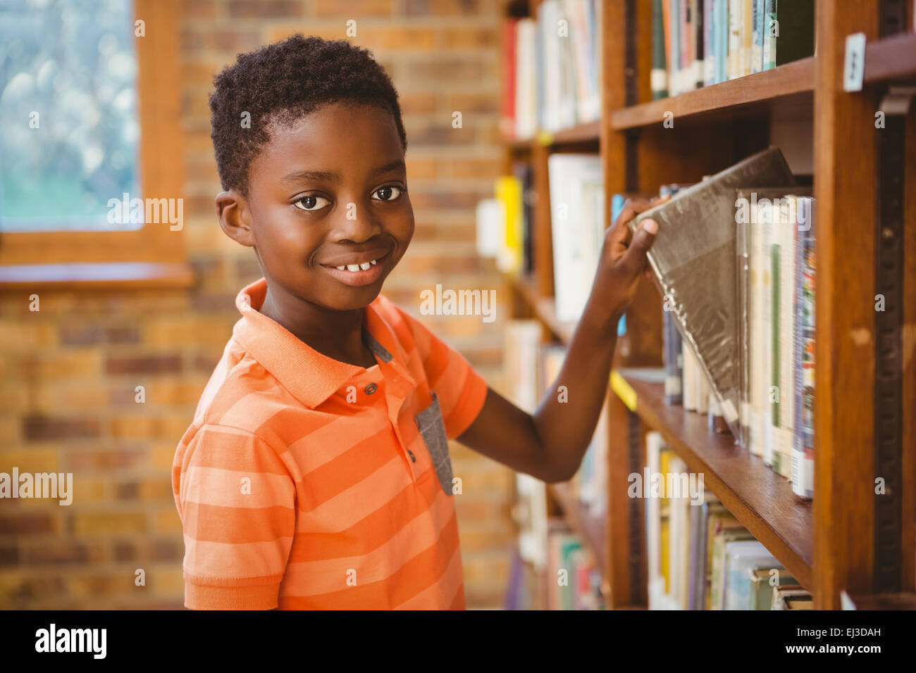 Portrait of boy selecting book in library Stock Photo - Alamy