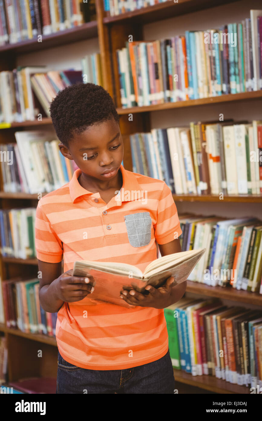 Cute boy reading book in library Stock Photo - Alamy