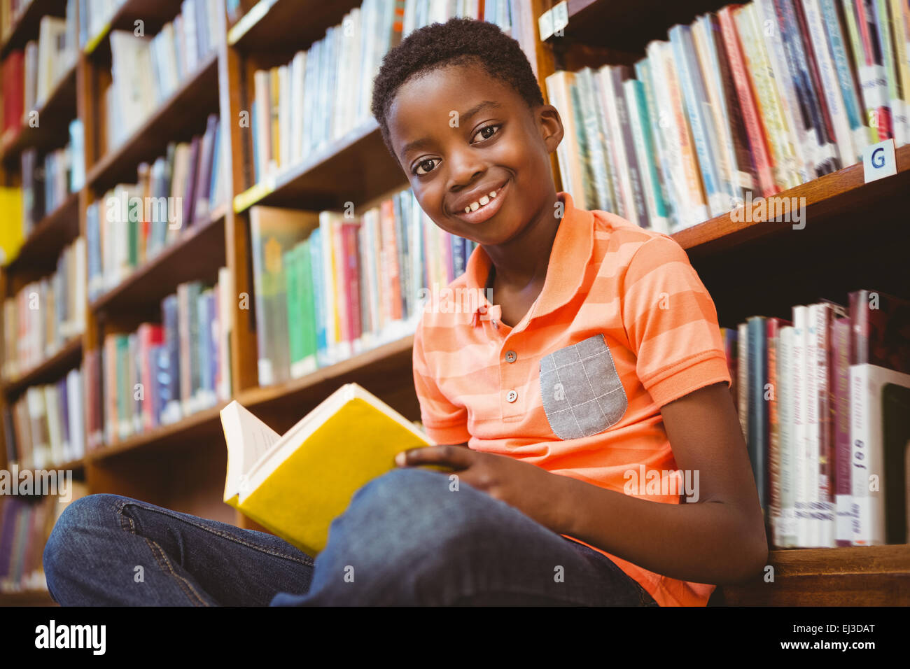 Cute boy reading book in library Stock Photo - Alamy