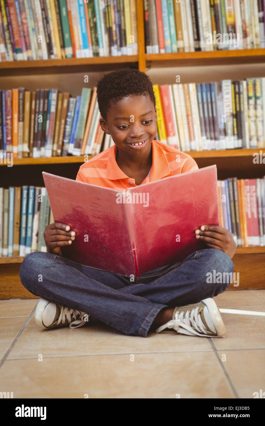 Cute boy reading book in library Stock Photo - Alamy