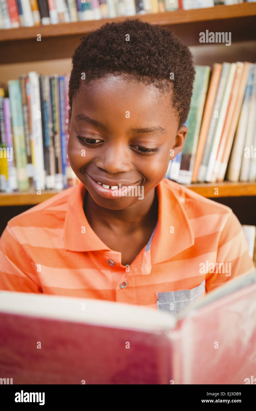Cute boy reading book in library Stock Photo - Alamy