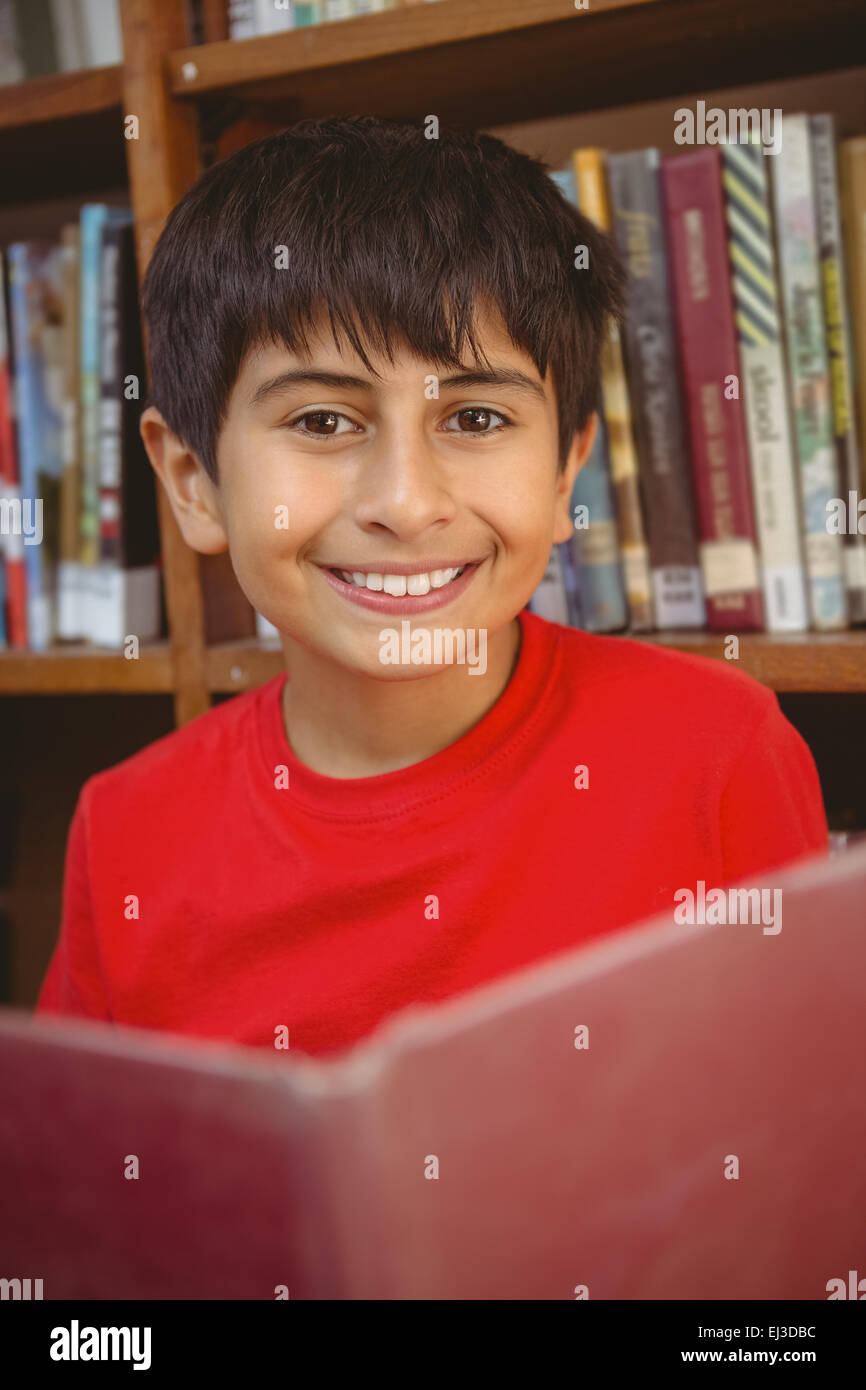 Cute boy reading book in library Stock Photo - Alamy