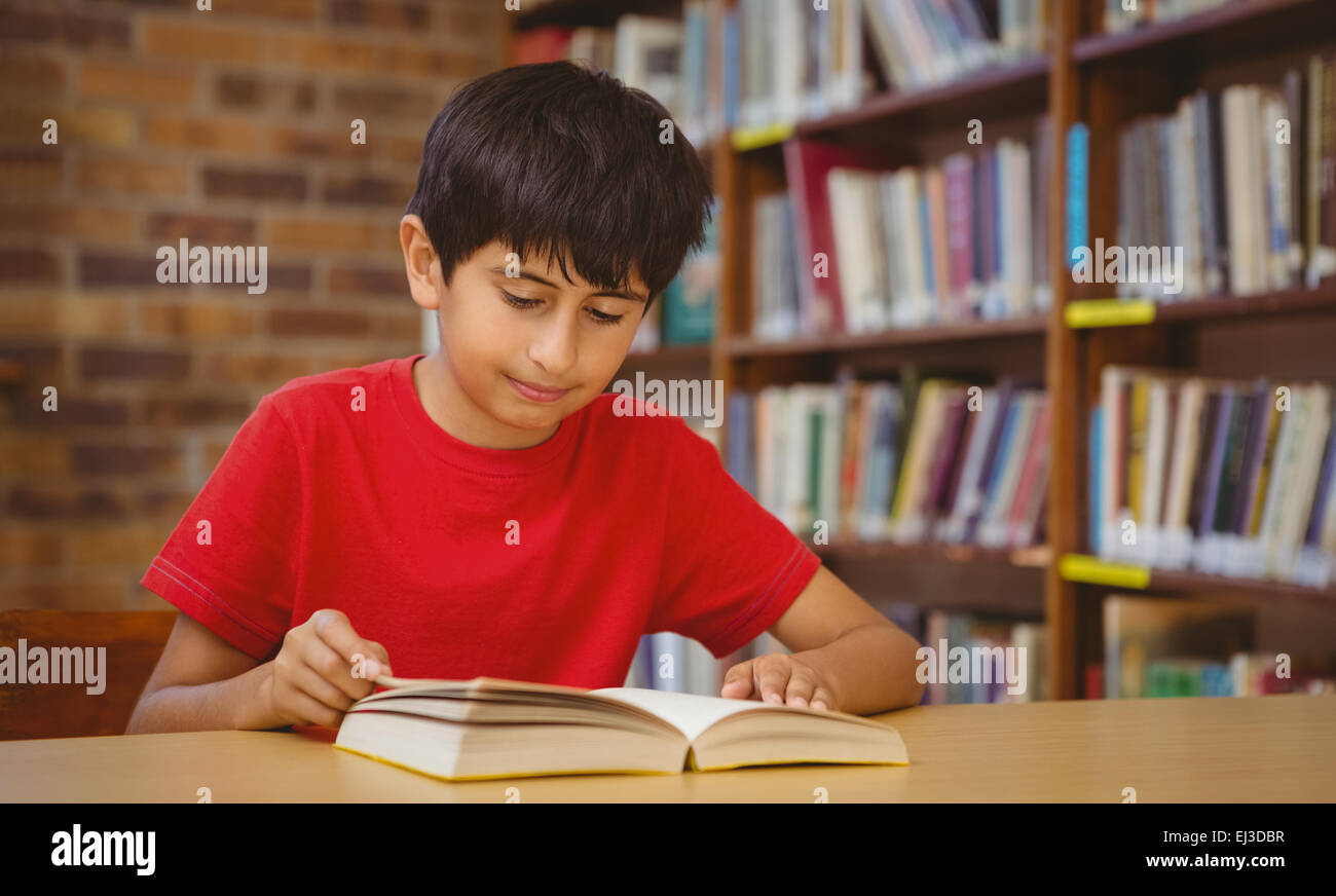 Cute boy reading book in library Stock Photo - Alamy