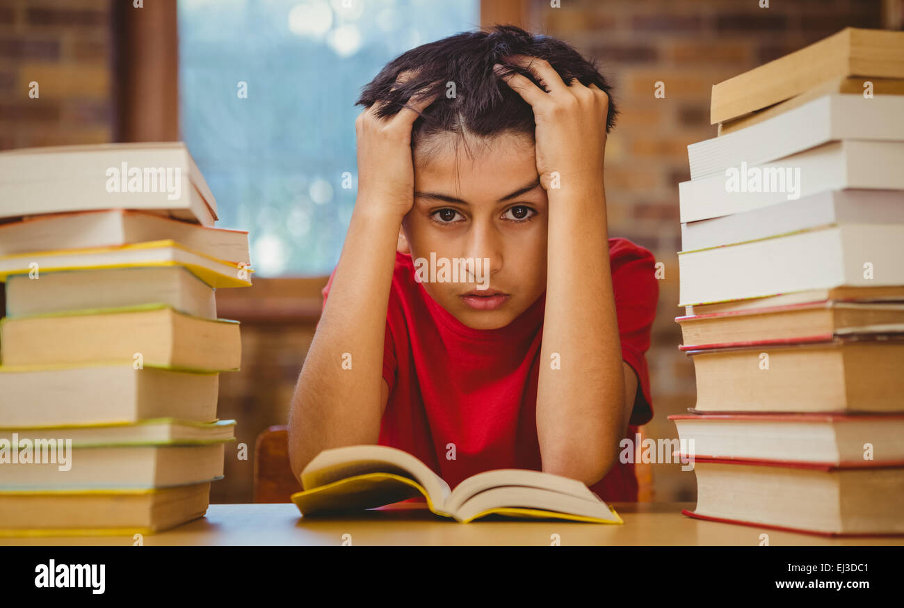 Tensed boy sitting with stack of books Stock Photo - Alamy