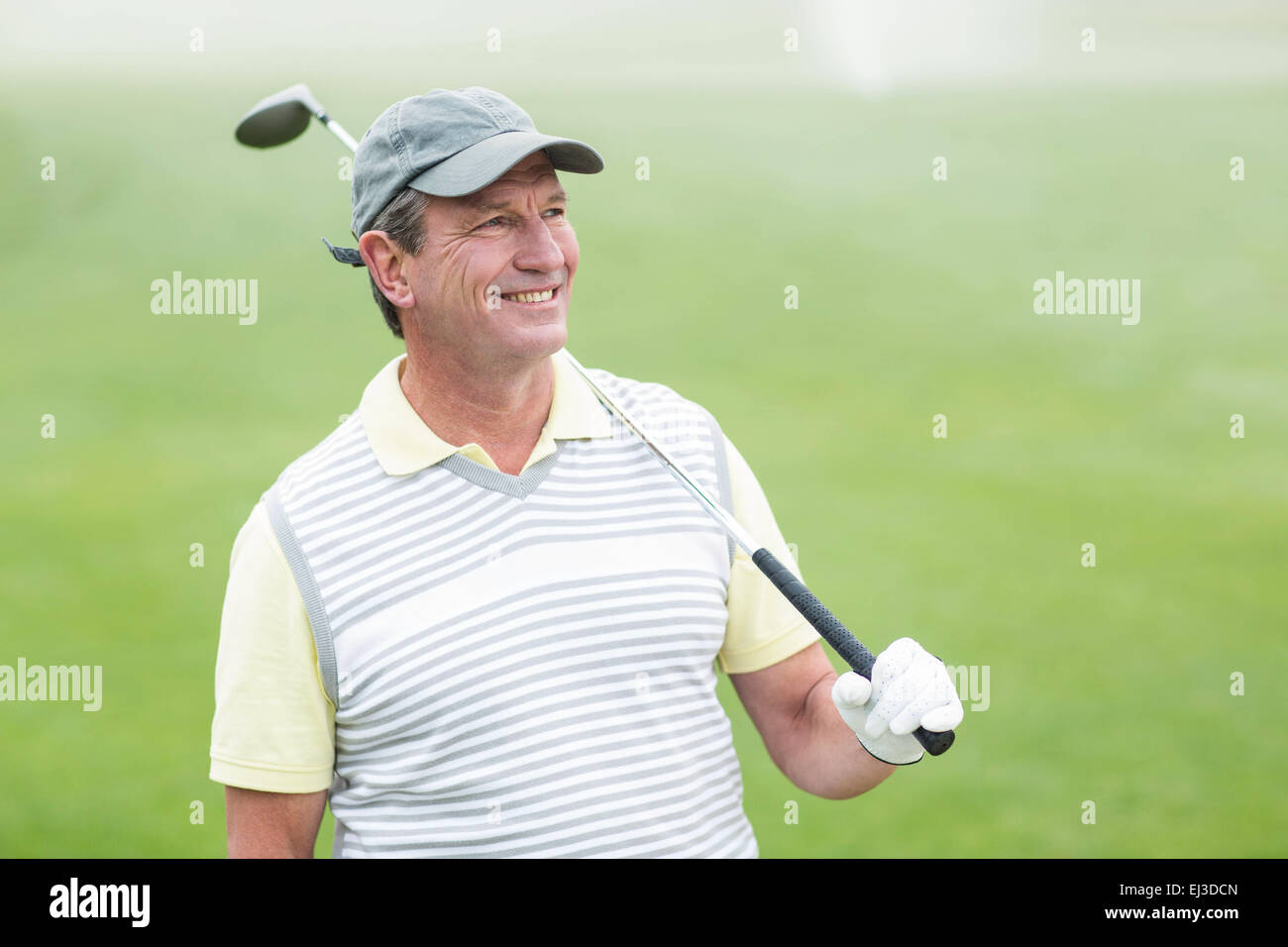 Golfer standing and swinging his club smiling at camera Stock Photo - Alamy