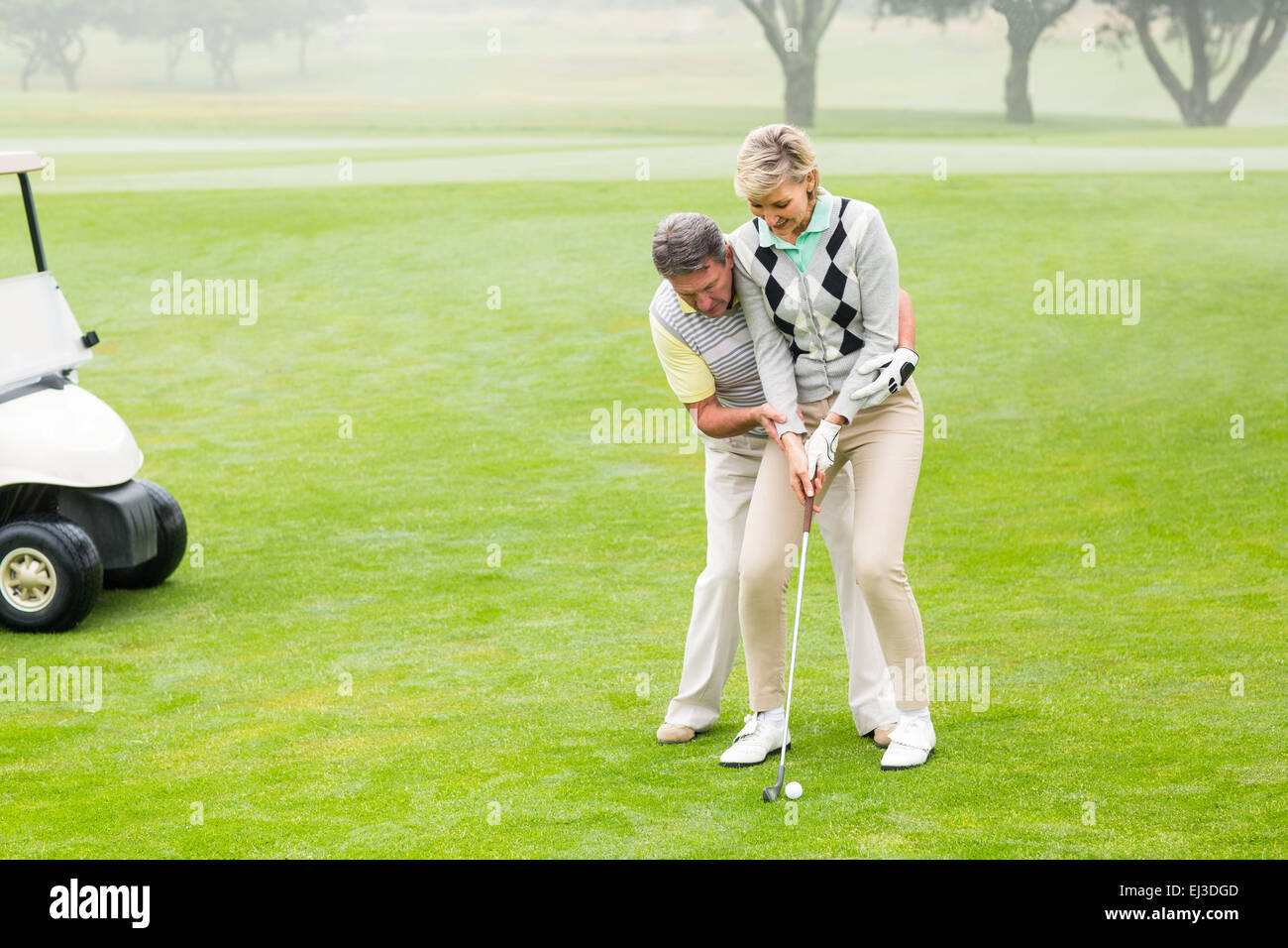 Golfing couple putting ball together Stock Photo - Alamy