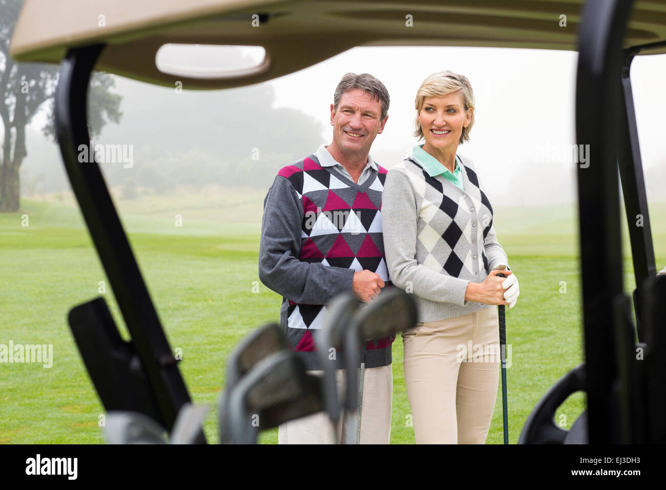 Happy golfing couple smiling Stock Photo - Alamy