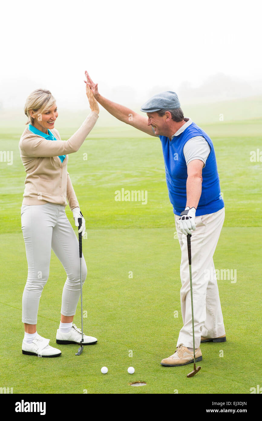 Golfing couple high fiving on the golf course Stock Photo - Alamy