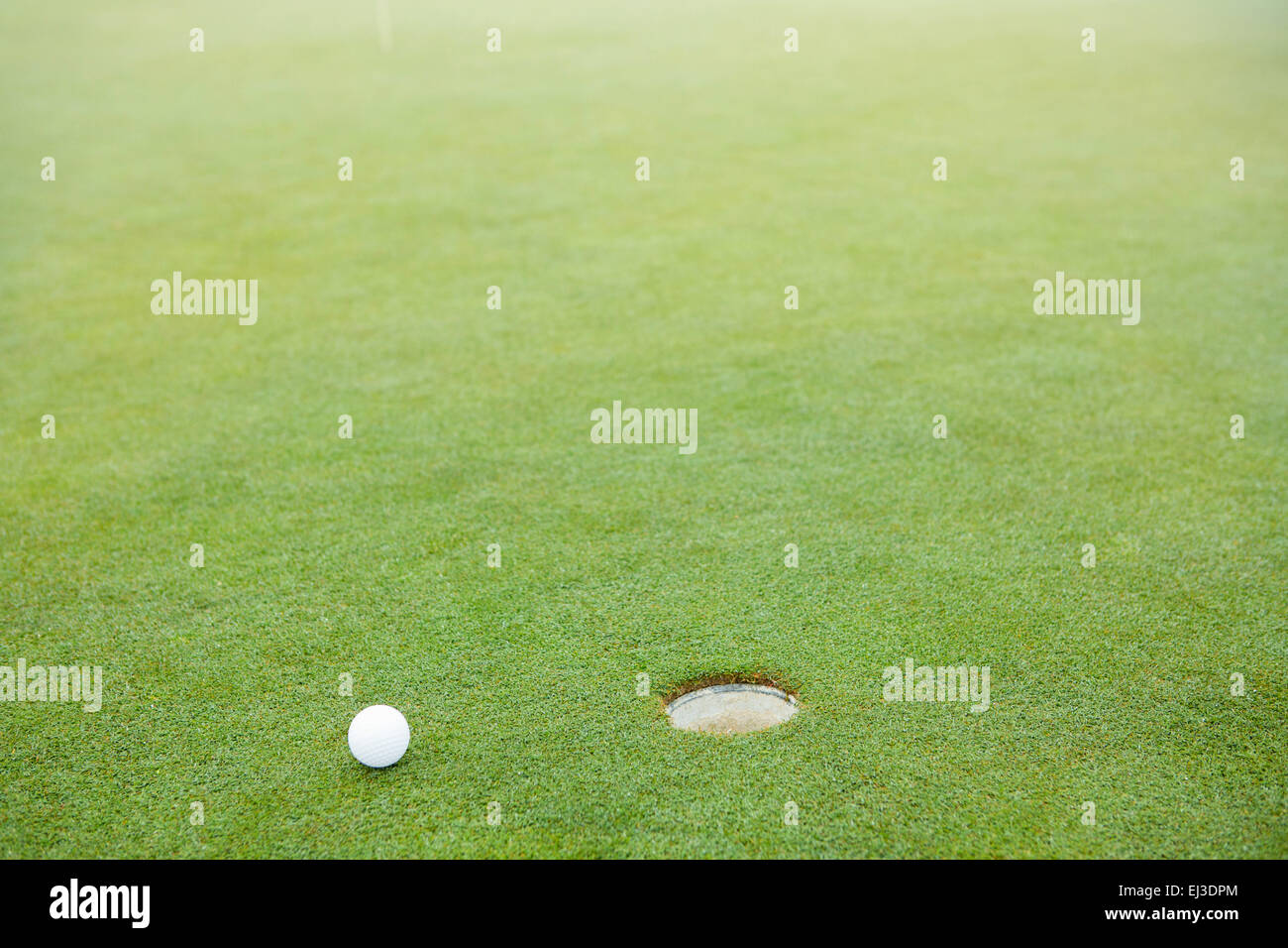 Golf ball next to hole Stock Photo - Alamy