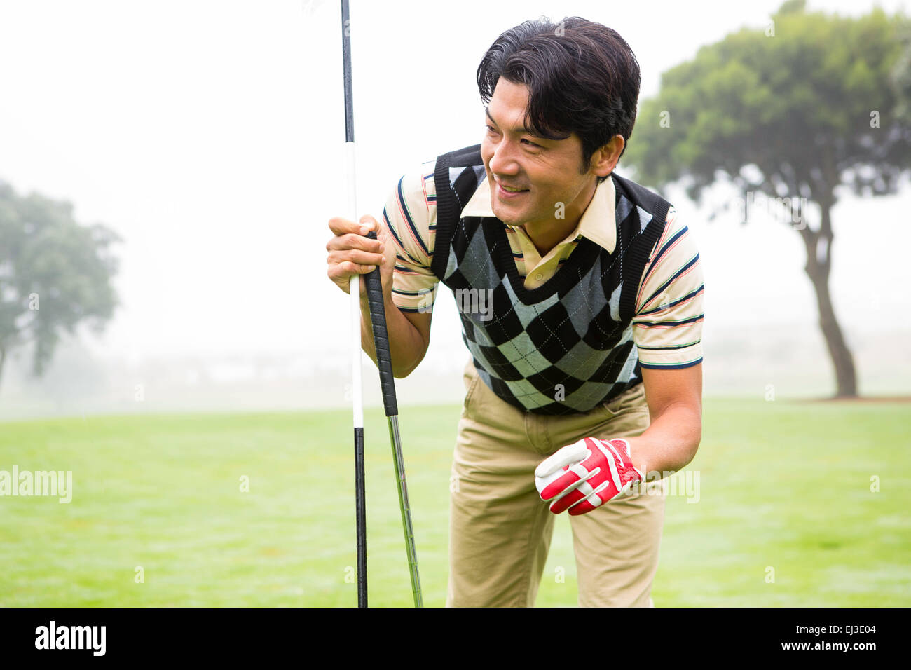 Golfer holding golf ball and club Stock Photo - Alamy