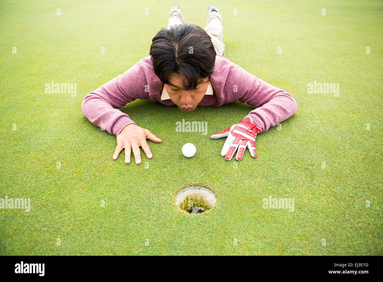 Golfer trying to flick ball into hole Stock Photo - Alamy