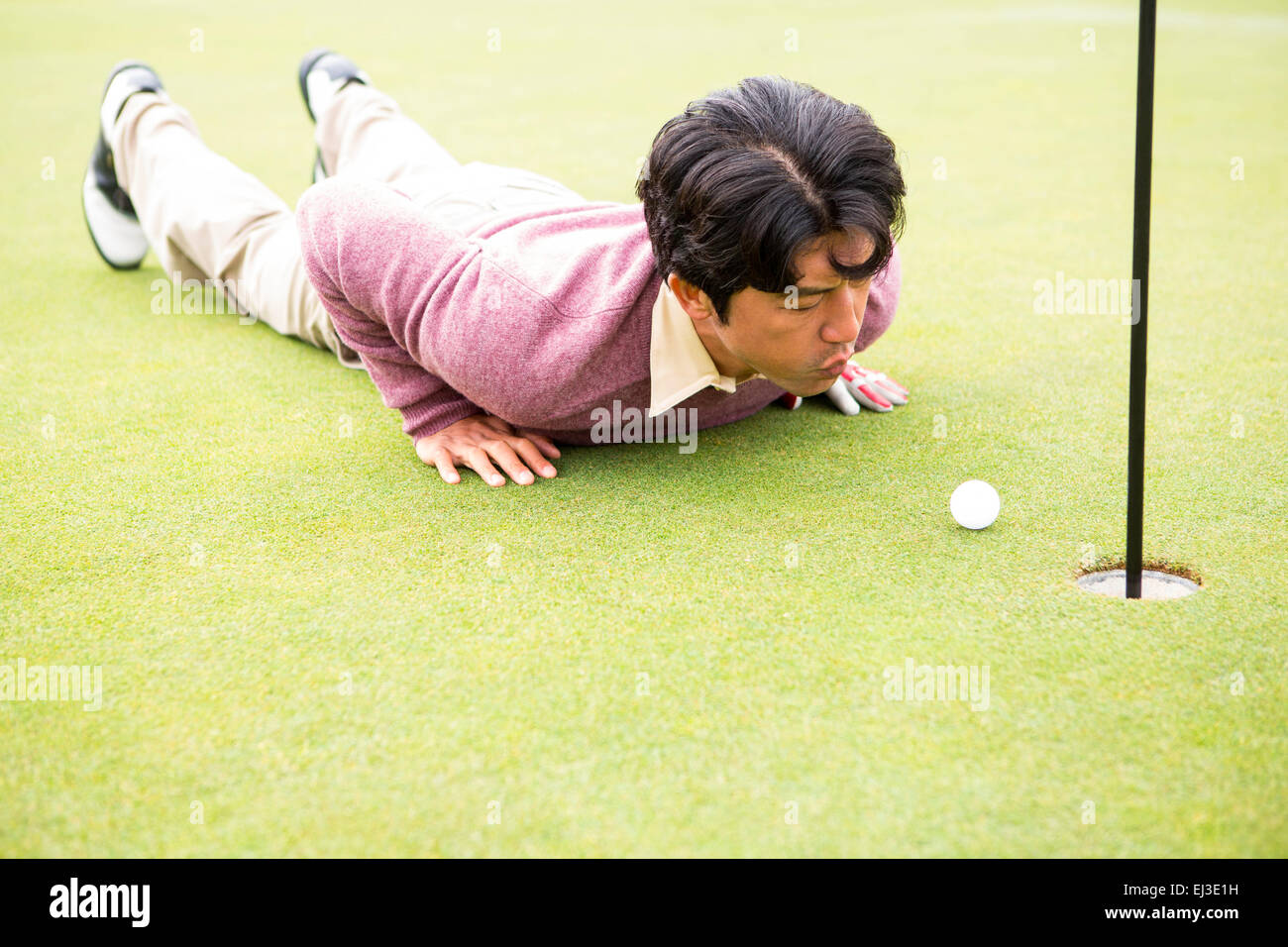 Golfer trying to flick ball into hole Stock Photo - Alamy