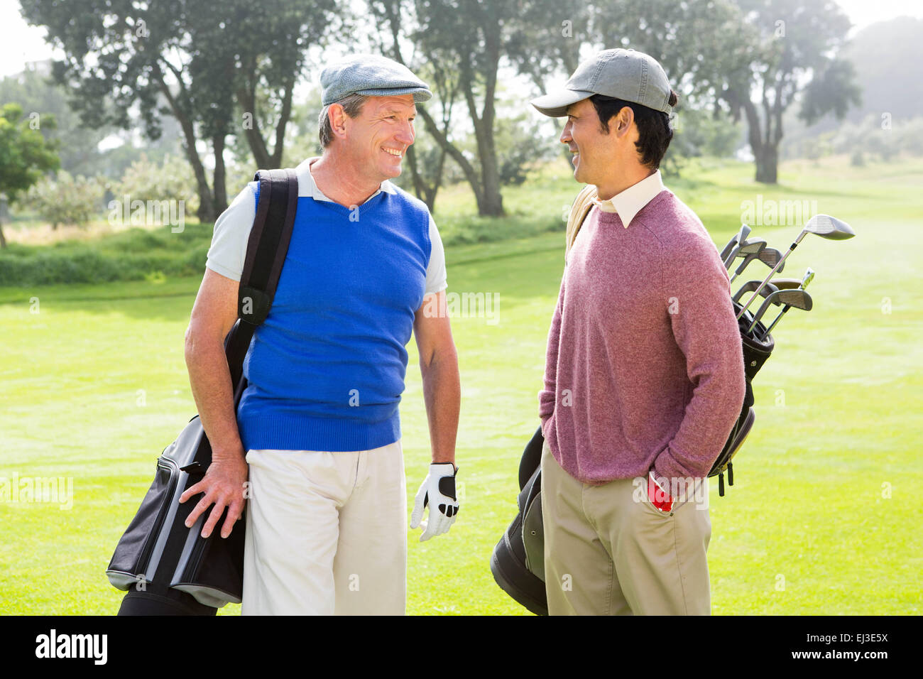 Golfing friends smiling and holding clubs Stock Photo - Alamy