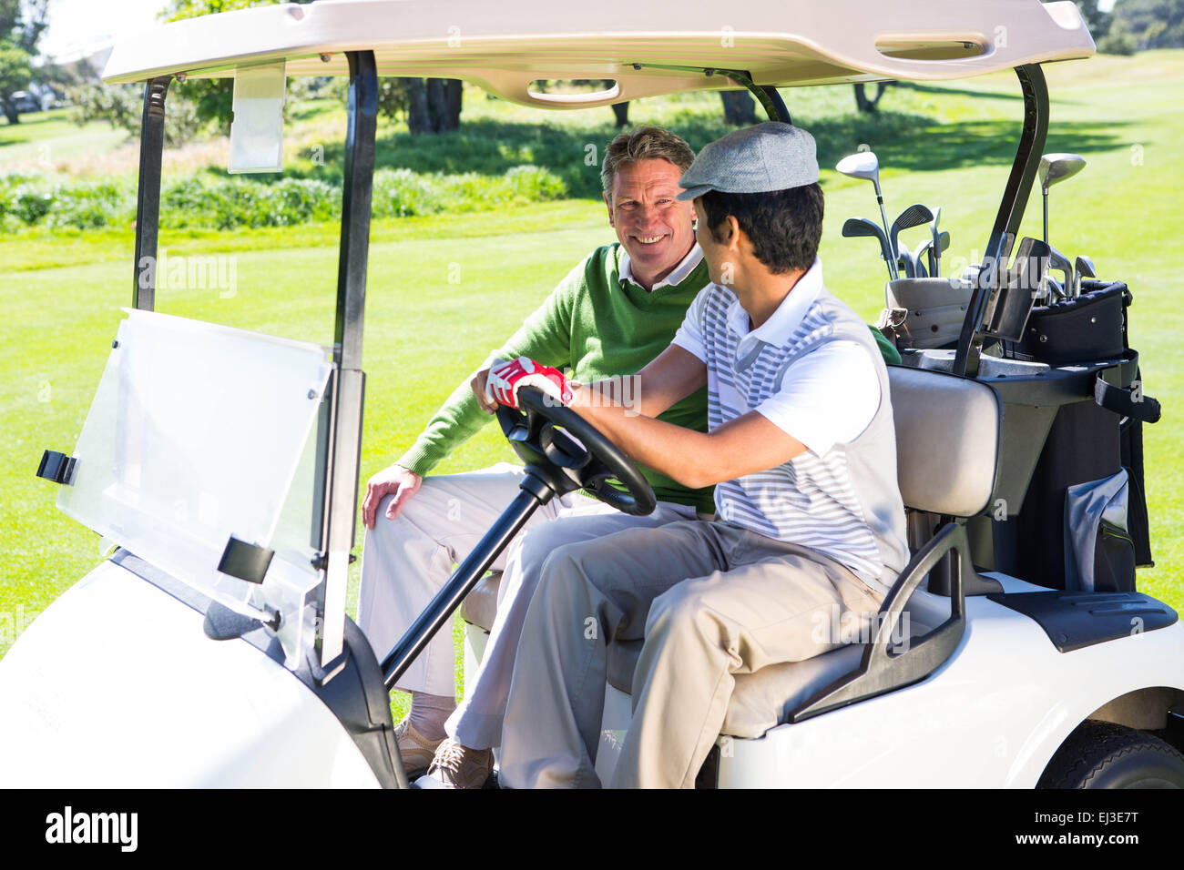 Golfing friends driving in their golf buggy Stock Photo - Alamy
