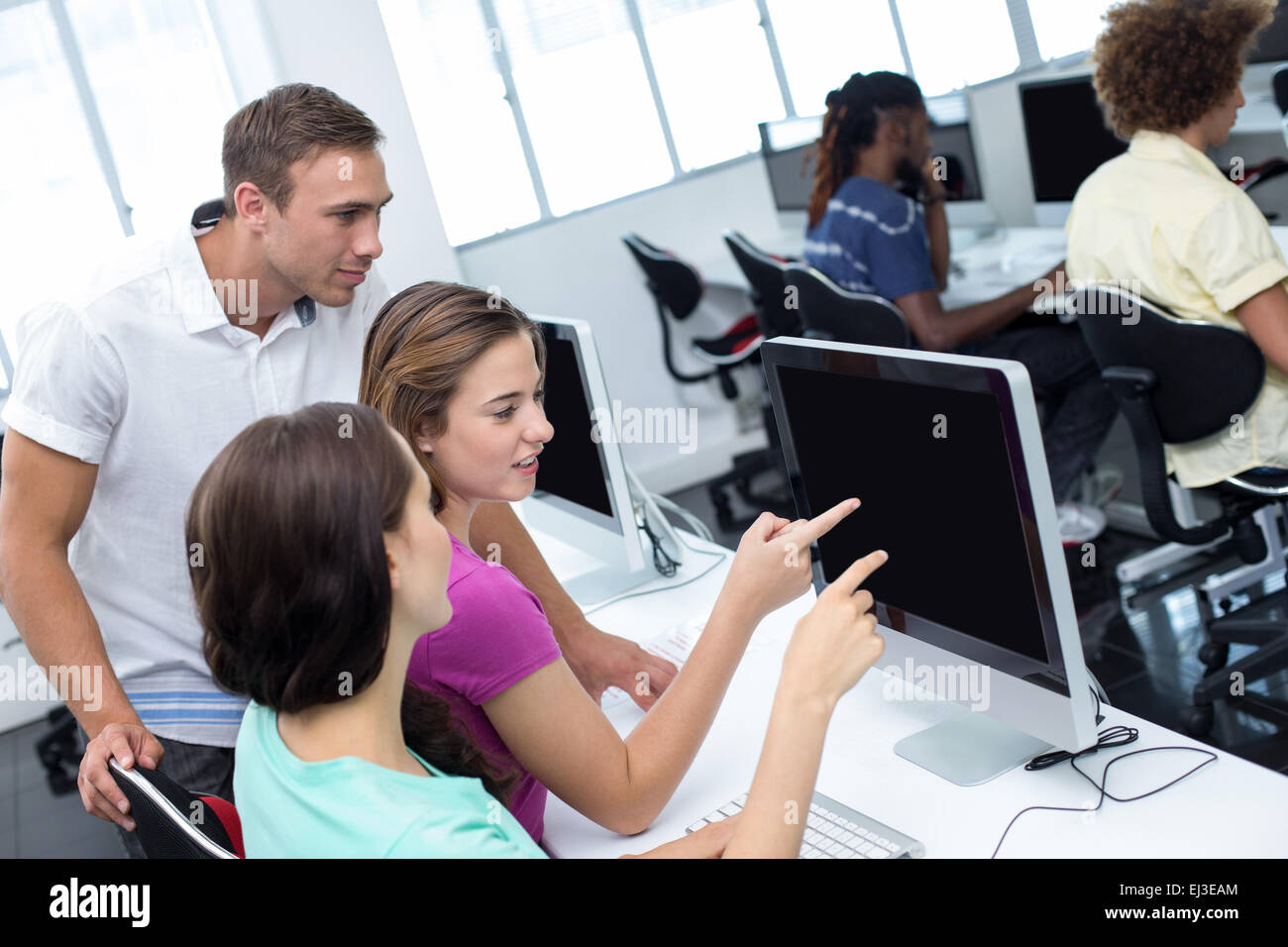 Computer teacher helping pretty female students Stock Photo - Alamy
