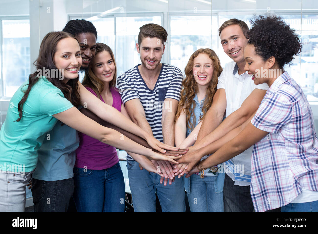 Happy college students placing hands together Stock Photo - Alamy