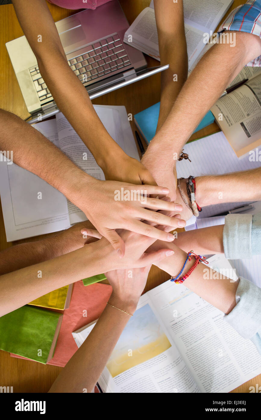 Students placing hands together over library table Stock Photo - Alamy