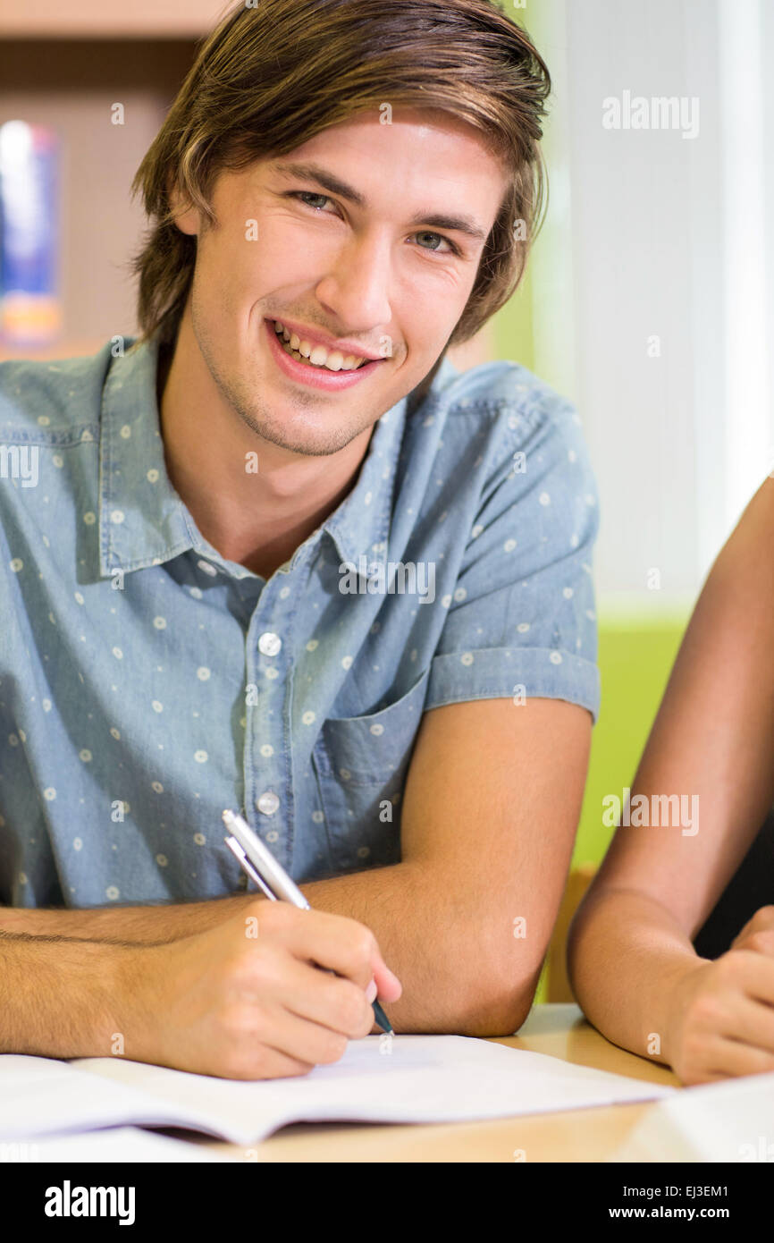 Happy male student doing homework in library Stock Photo - Alamy