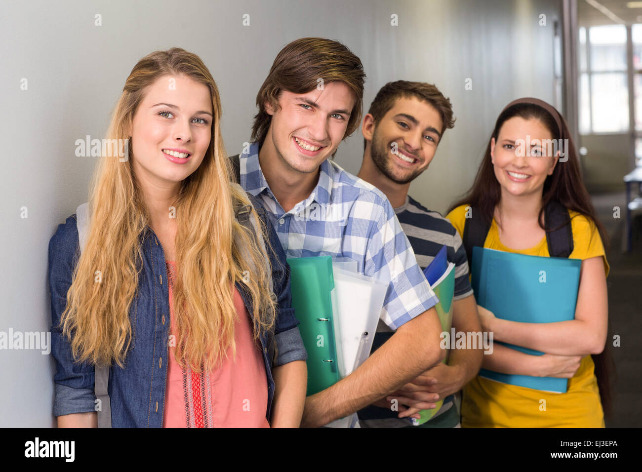 Students holding folders at college corridor Stock Photo - Alamy
