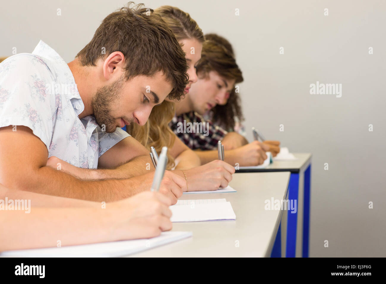 Students writing notes in classroom Stock Photo - Alamy