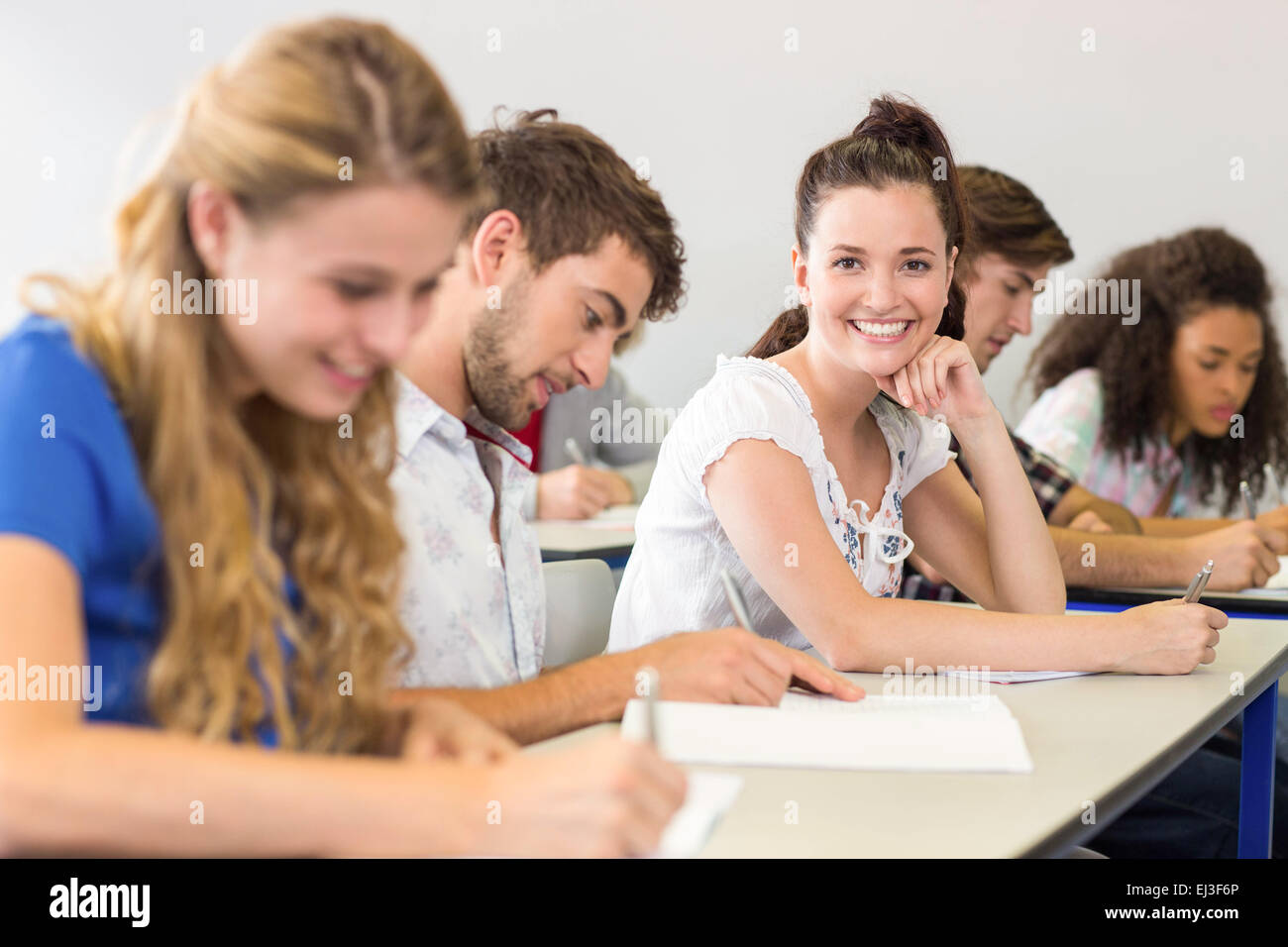 Students writing notes in classroom Stock Photo - Alamy