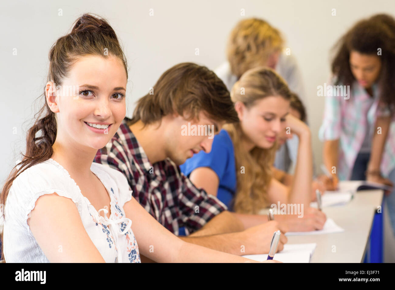 Students writing notes in classroom Stock Photo - Alamy