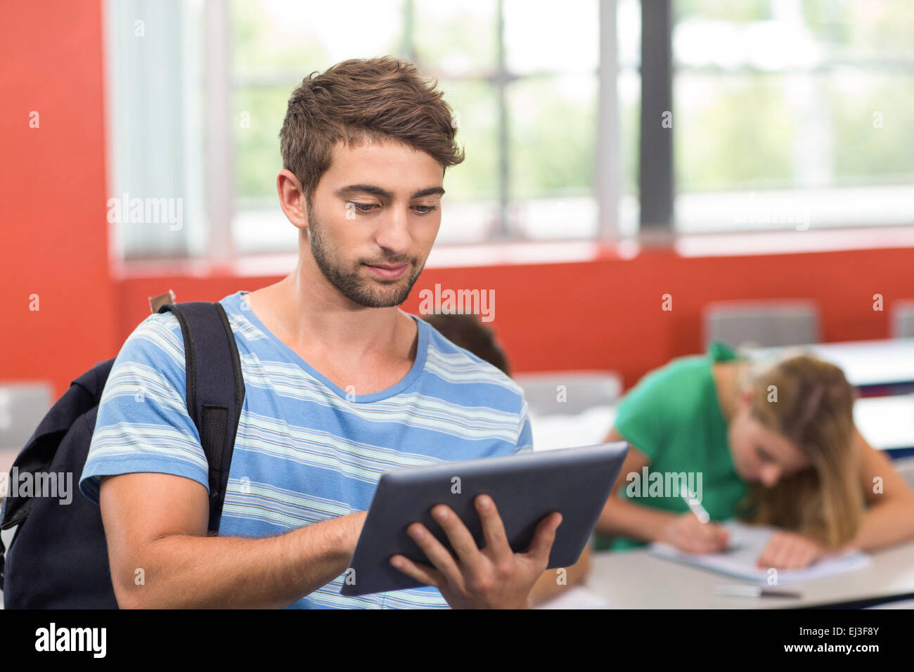 Male student using digital tablet in classroom Stock Photo - Alamy