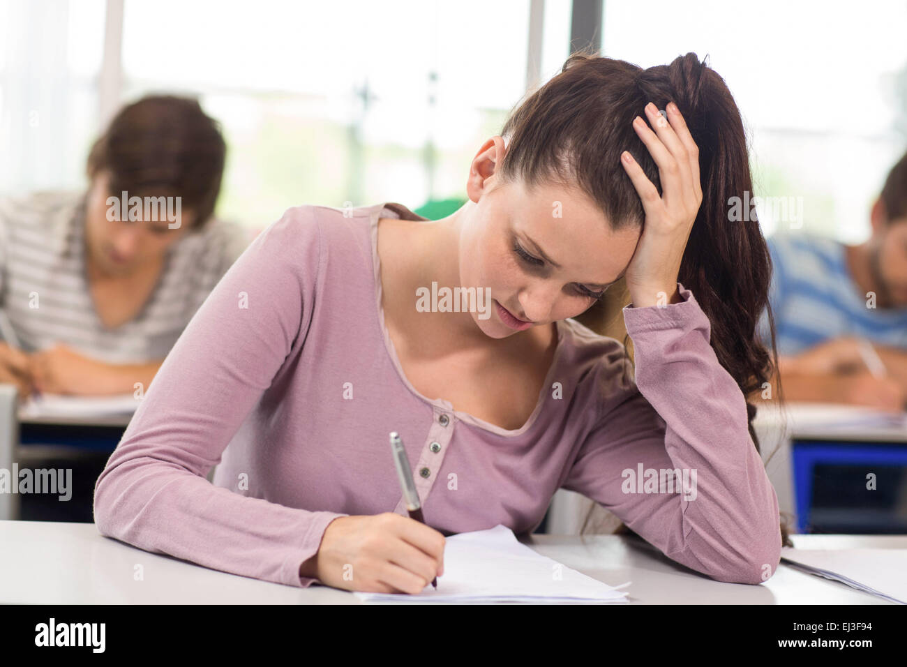Female student writing notes in classroom Stock Photo - Alamy