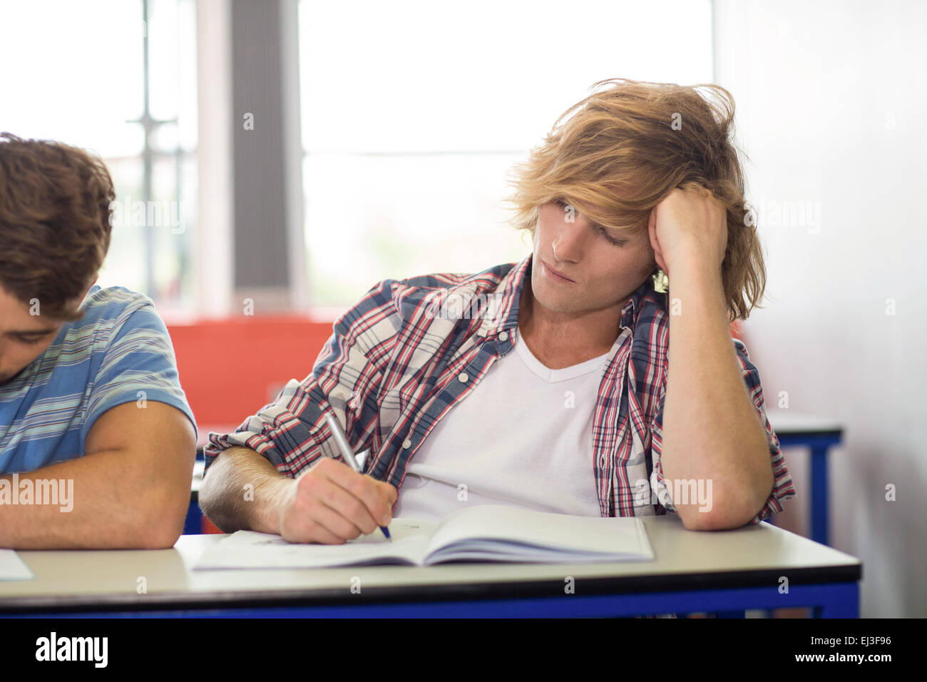 Male student writing notes in classroom Stock Photo - Alamy