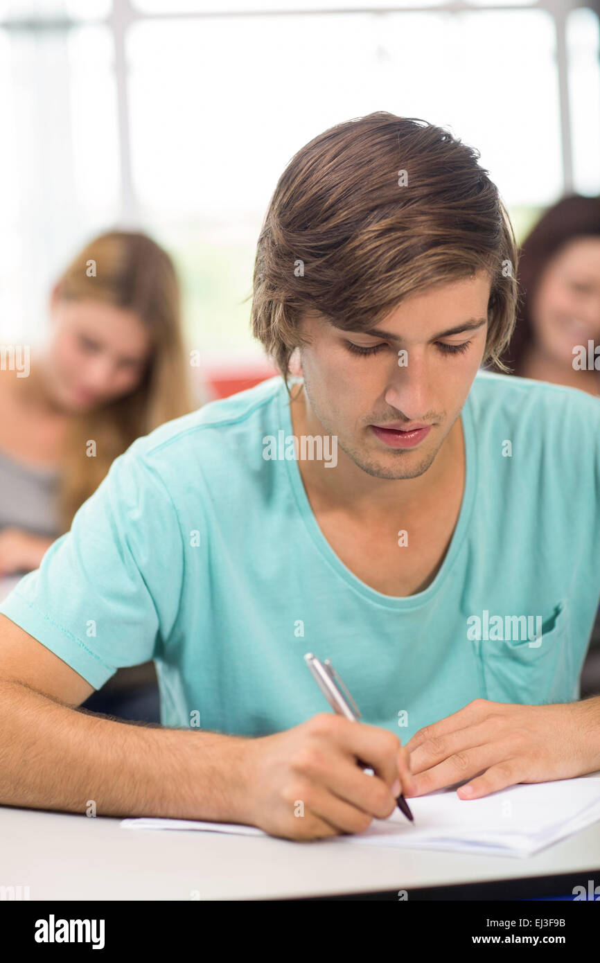 Male student writing notes in classroom Stock Photo - Alamy