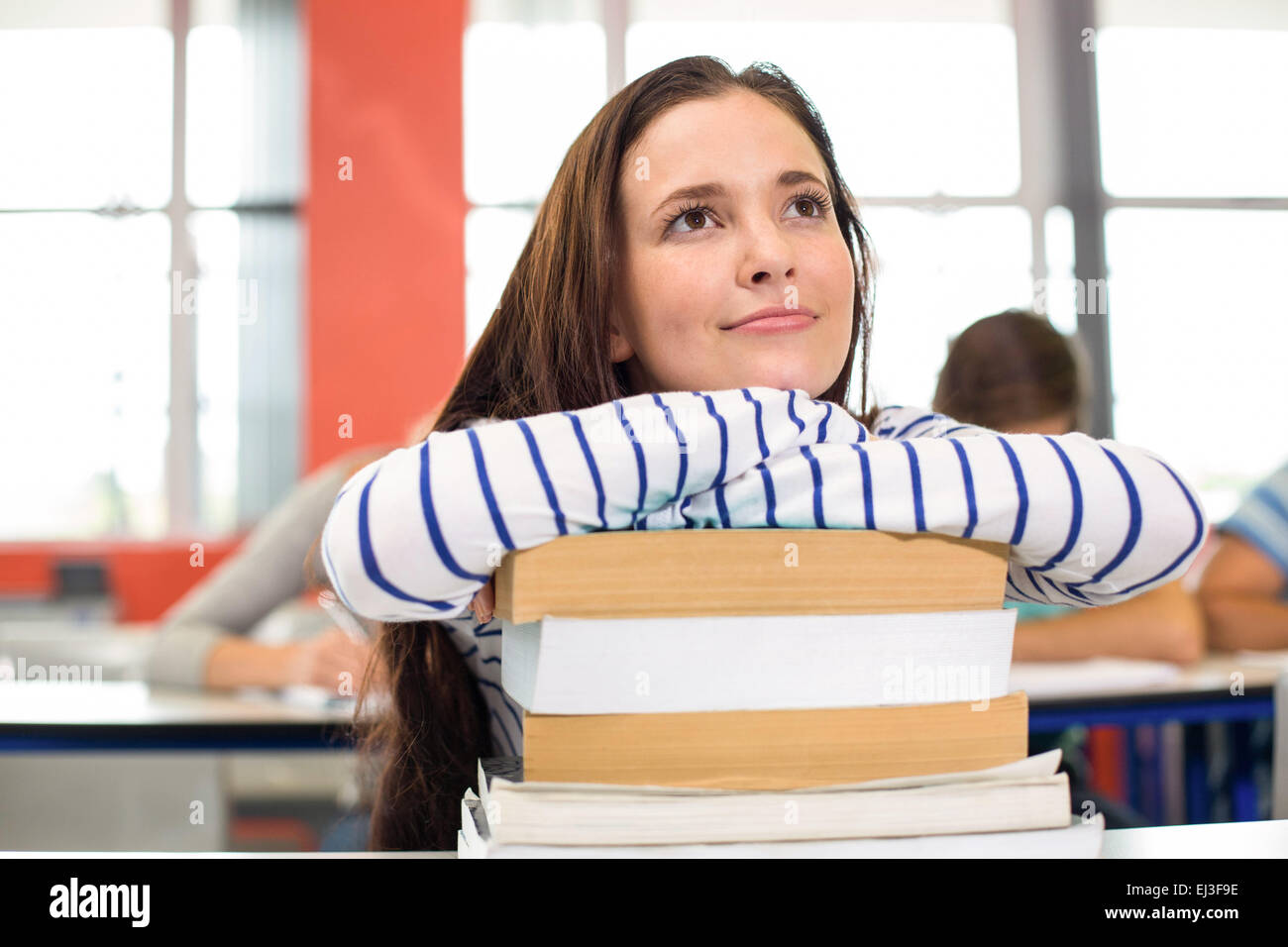 Thoughtful student with books in classroom Stock Photo - Alamy
