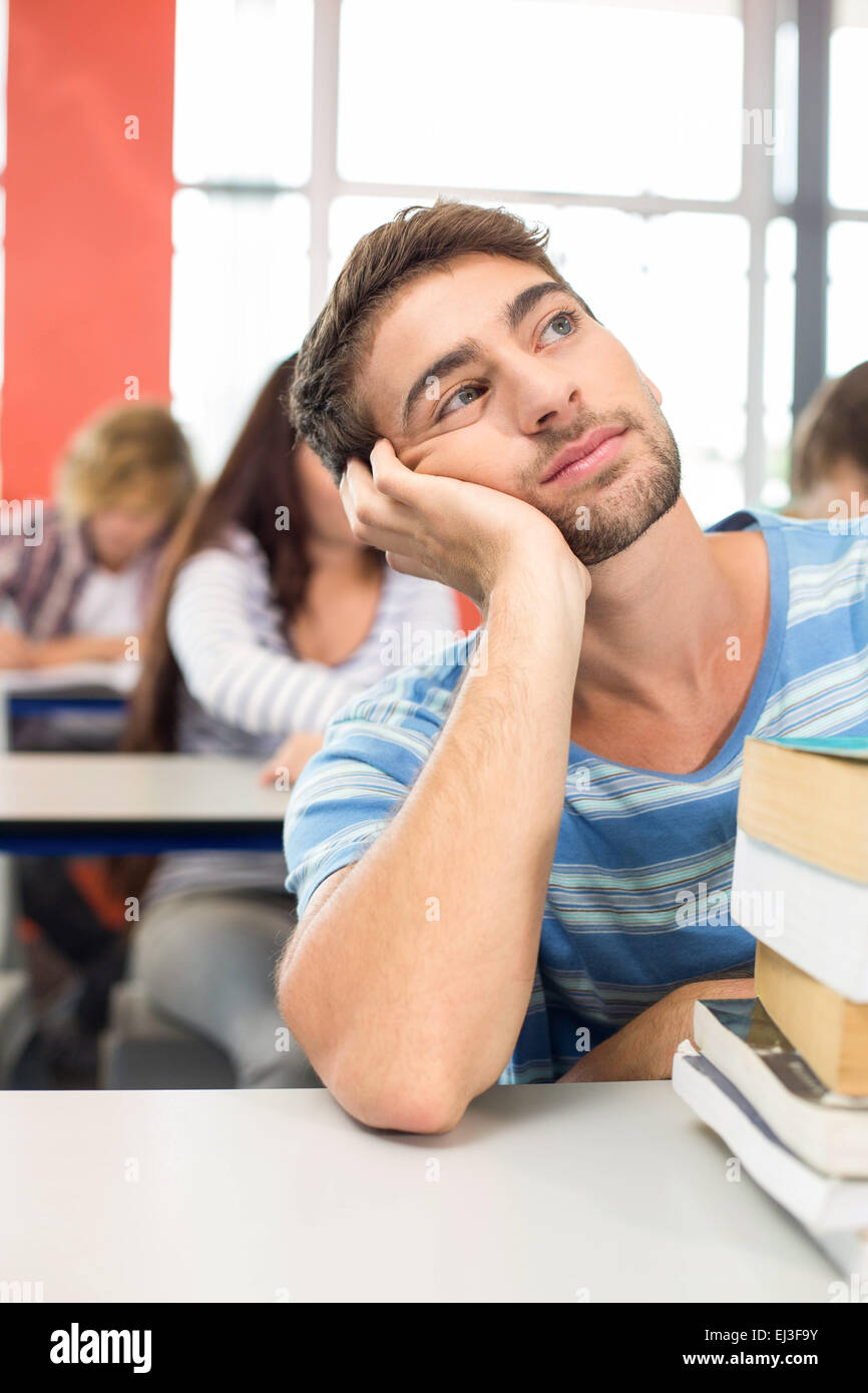 Thoughtful student with books in classroom Stock Photo - Alamy