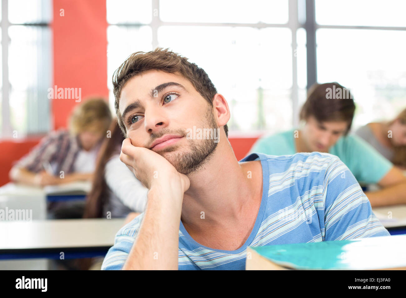 Thoughtful student with books in classroom Stock Photo - Alamy