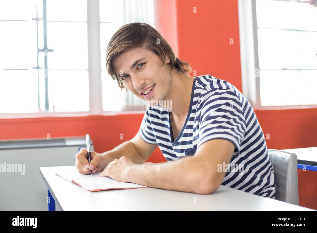 Male student writing notes in classroom Stock Photo - Alamy