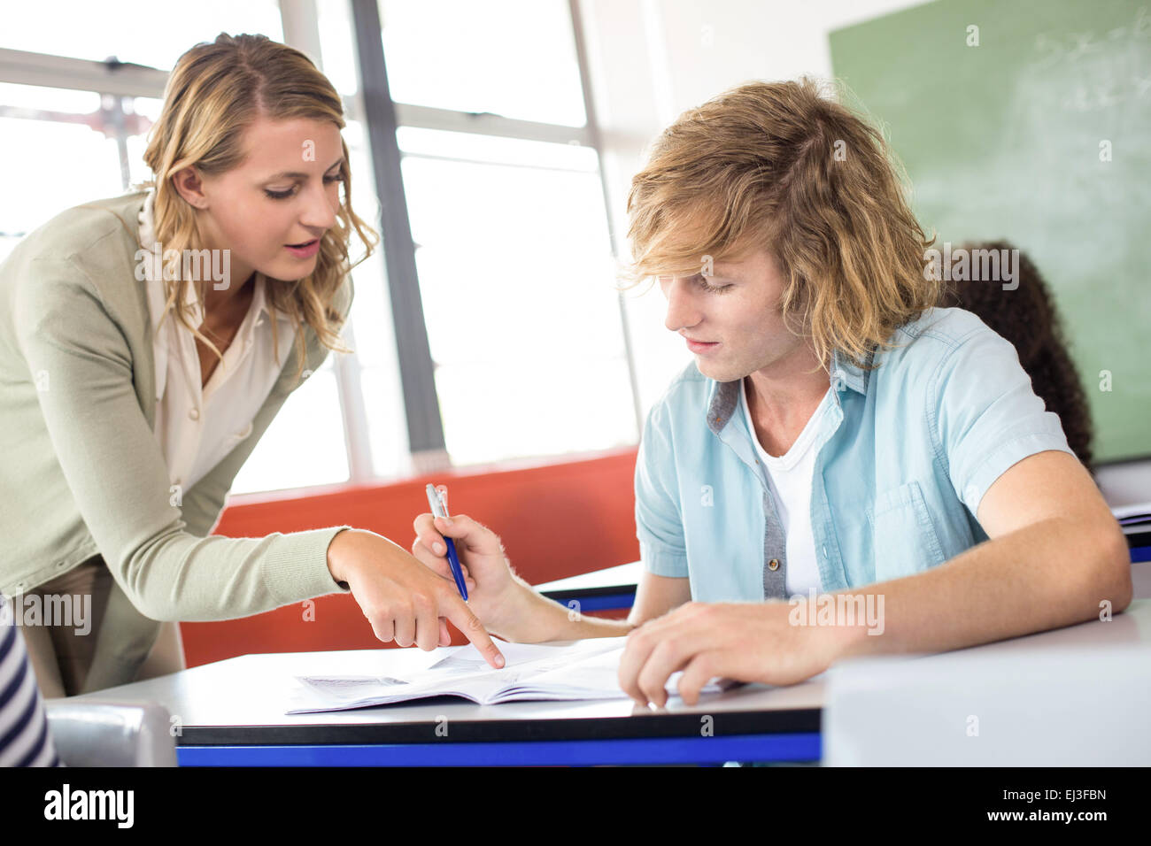 Teacher helping student in class Stock Photo - Alamy