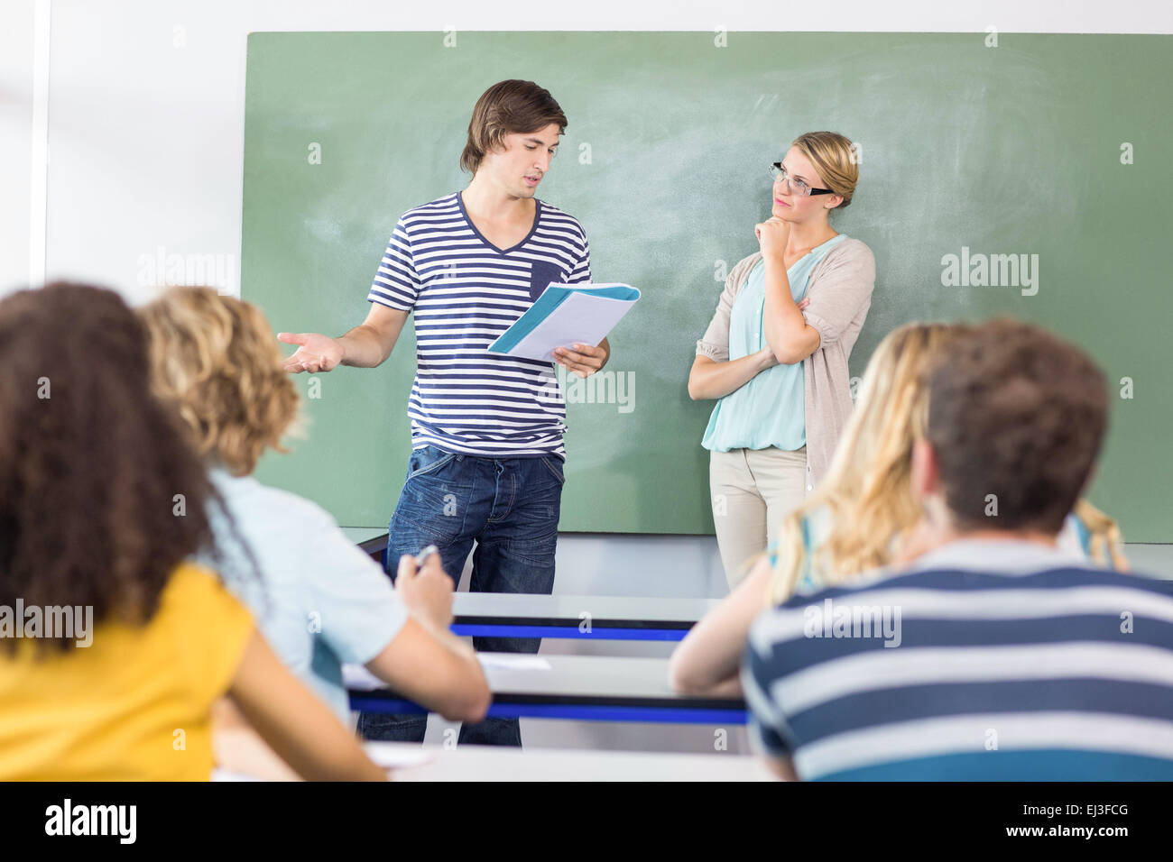 Student explaining notes besides teacher in class Stock Photo - Alamy