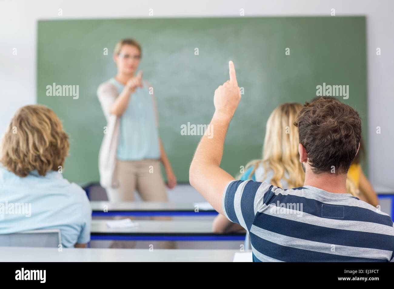 Student raising hand in classroom hi-res stock photography and images ...