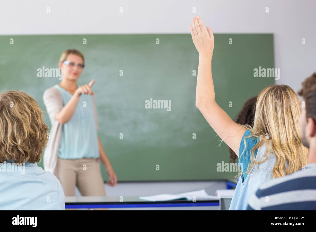 Student raising hand in classroom Stock Photo - Alamy