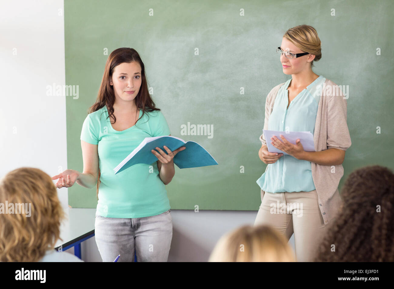 Student explaining notes besides teacher in class Stock Photo - Alamy